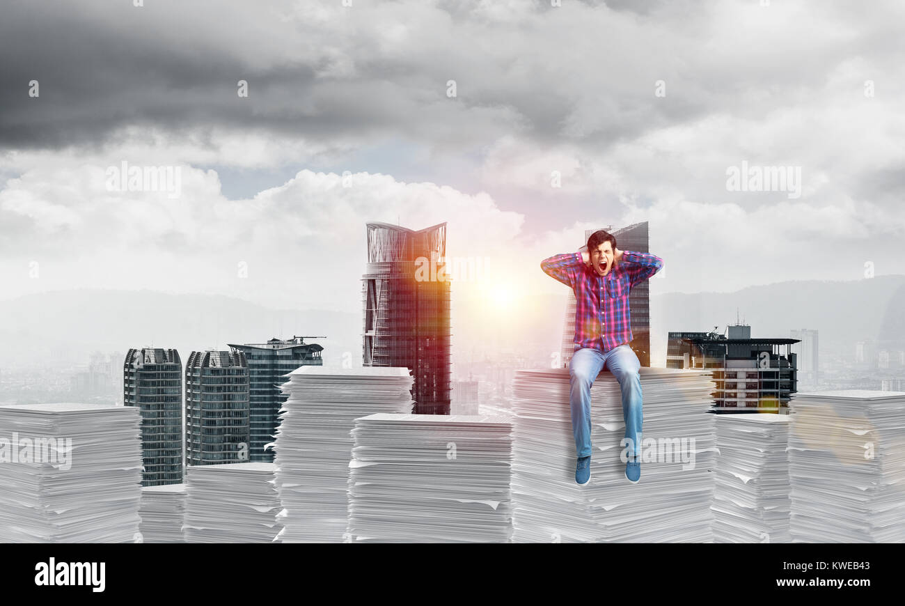 Attractive man sitting on pile of paper documents Stock Photo - Alamy