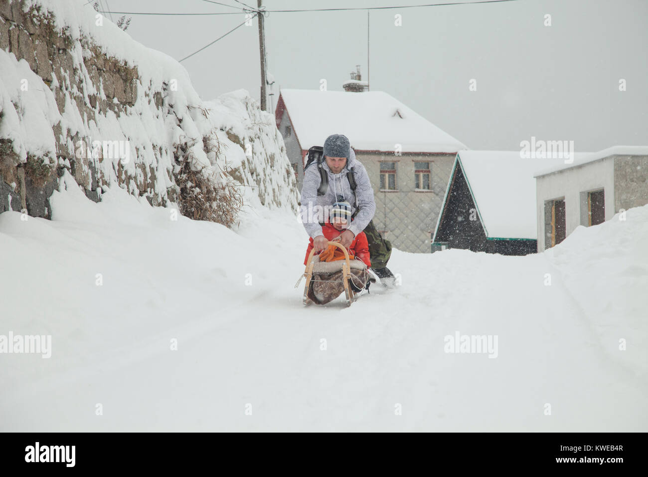 Man towing sleigh on snowy hill and road in winter time with blue sky ...