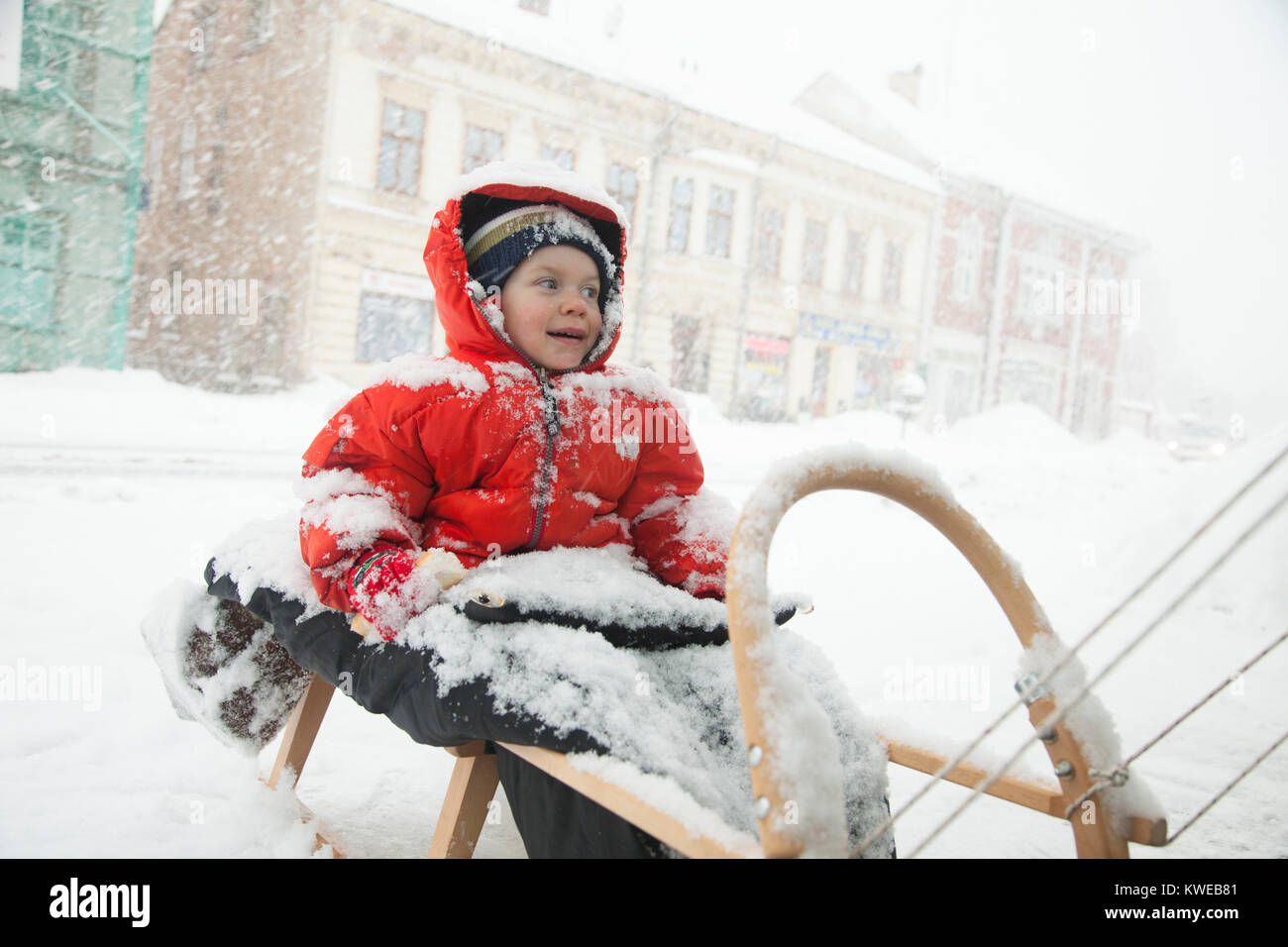 Man towing sleigh on snowy hill and road in winter time with blue sky ...