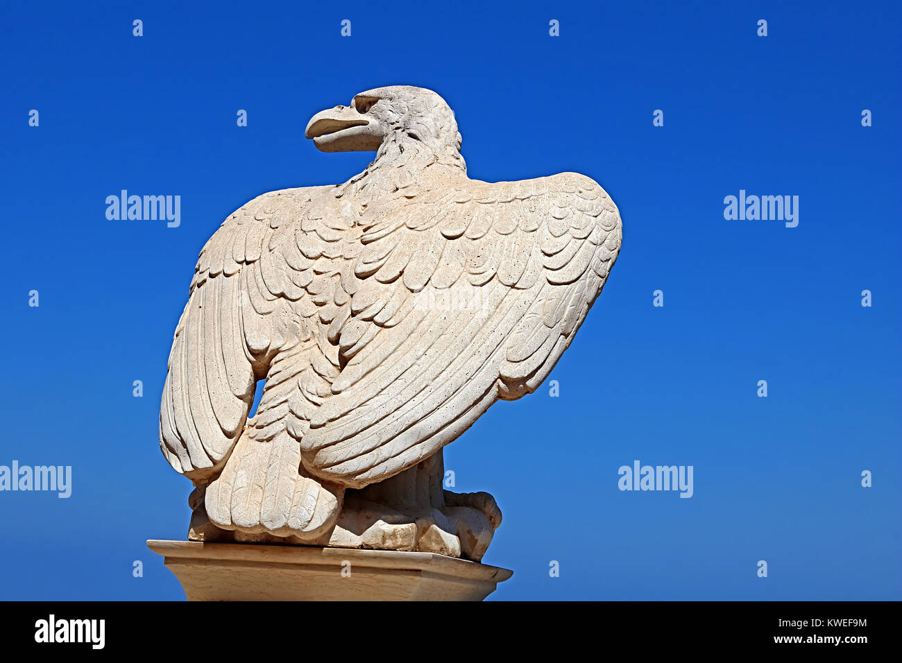 White stone eagle guards the gate to Bahai Gardens over blue sky in ...