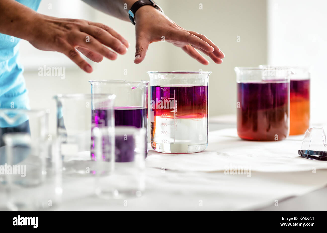 Woman is taking beakers with liquid in bare hands Stock Photo - Alamy