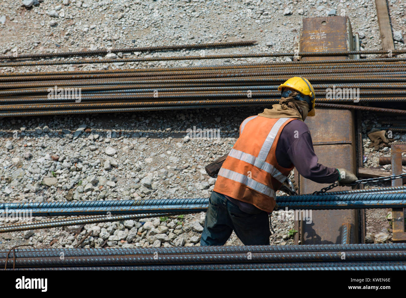 A worker on a construction site helping to move steel reinforcing bars ...