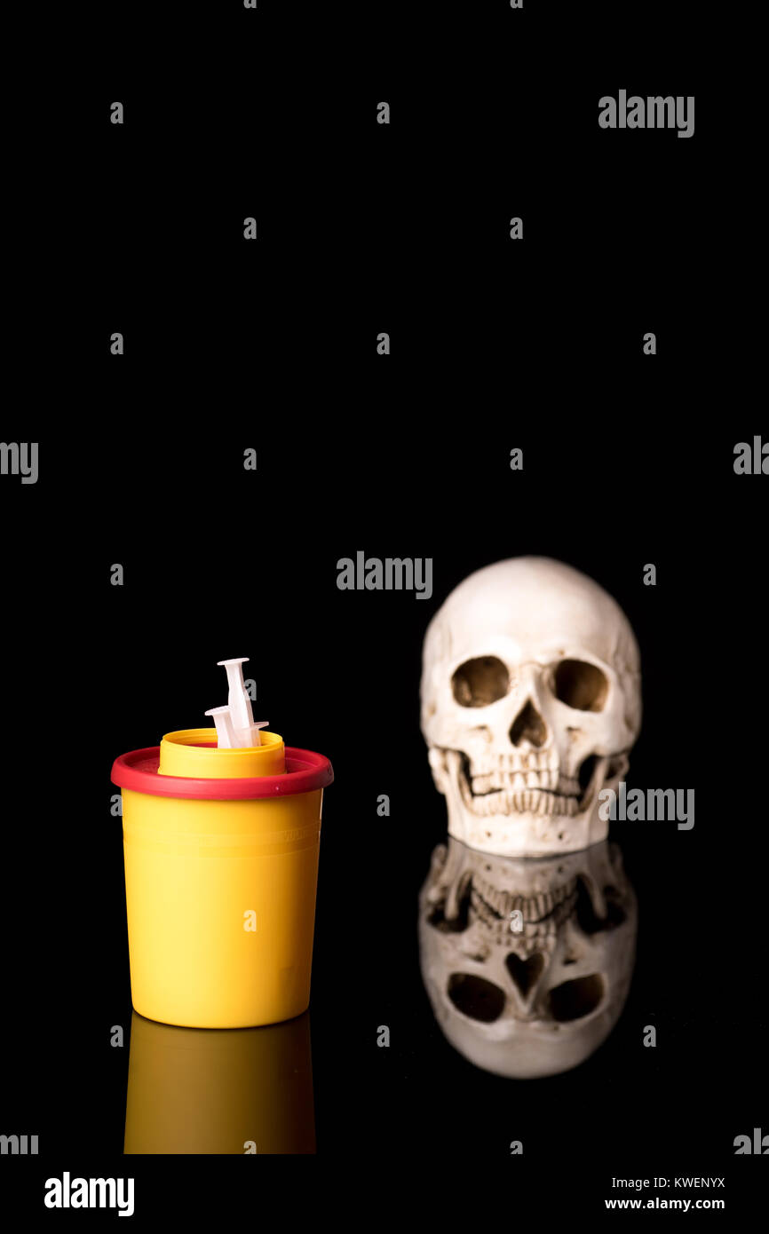 Skull, syringe and yellow waste container, isolated on black with ...