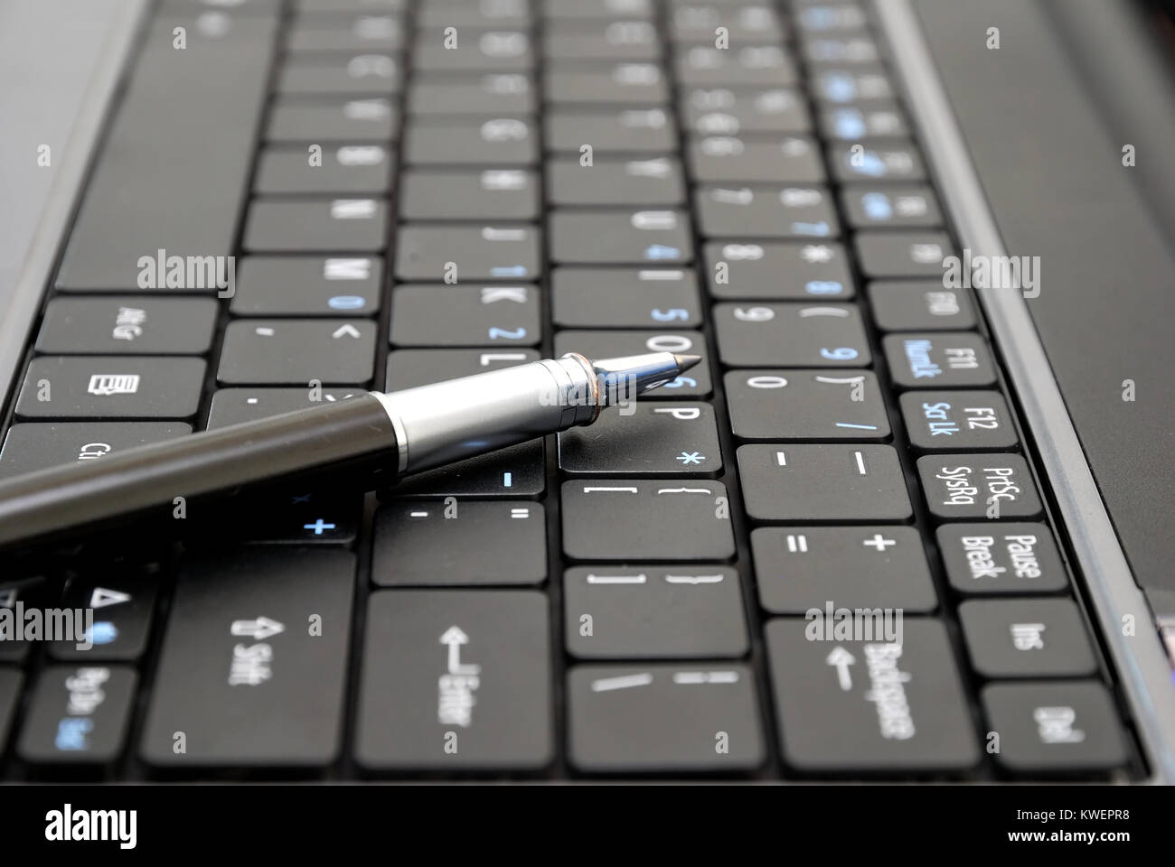 Pen on black laptop keyboard signifying concepts such as electronics ...