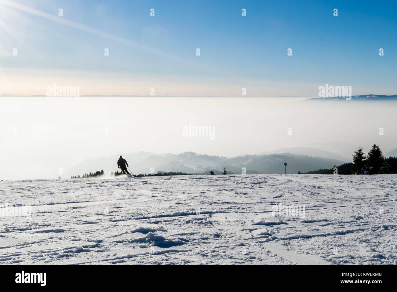 Single skier silhouette at a the piste with fog and clouds in the ...