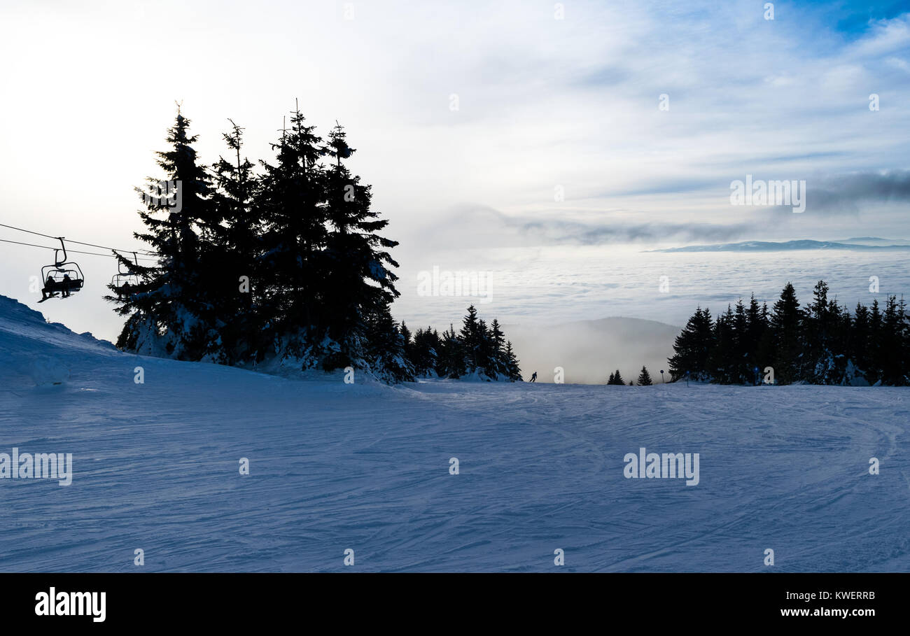 Single skier silhouette at a the piste with fog and clouds in the ...