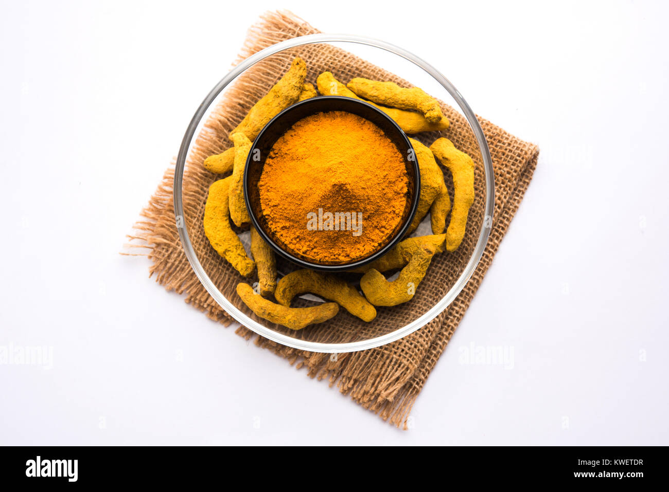 Turmeric powder in GLASS bowl with raw dried turmeric over plain ...