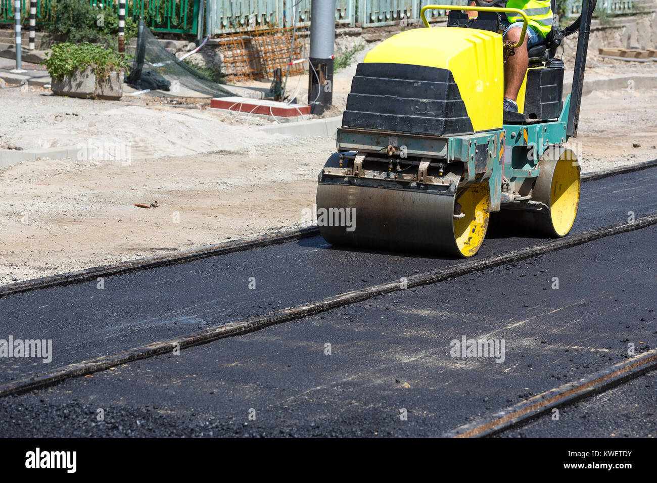 Small steamroller along tram car's railroad lines. Road construction ...