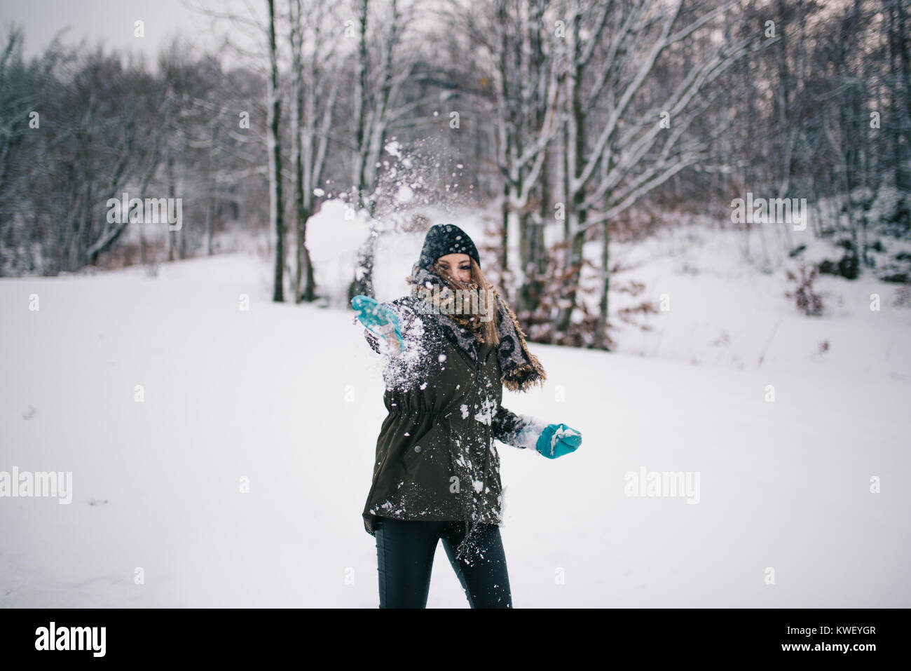 Happy woman throwing snowball Stock Photo - Alamy