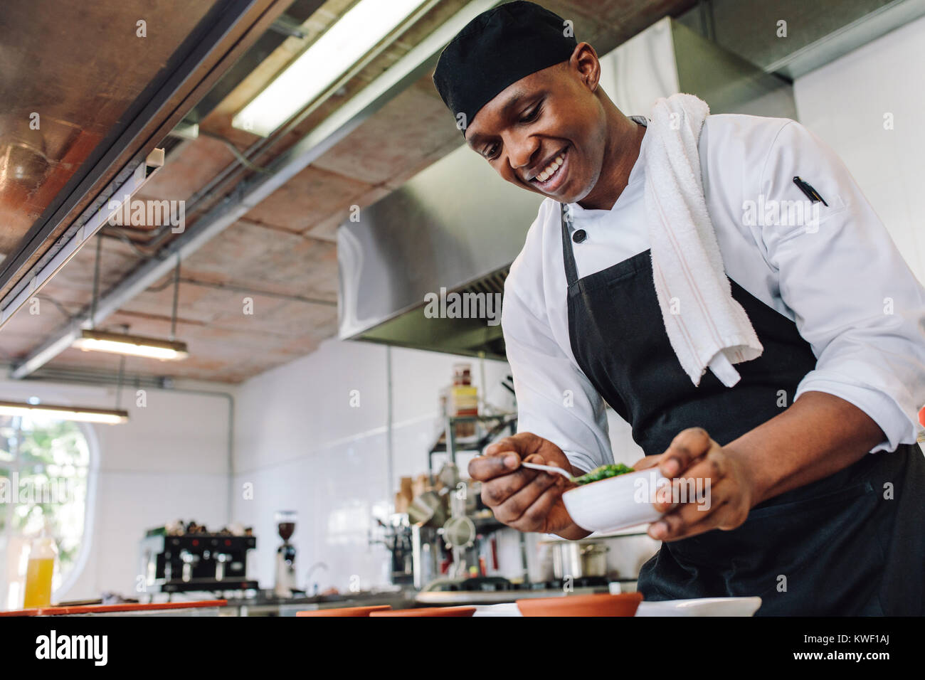 Gourmet chef in uniform cooking in a commercial kitchen. Happy male ...