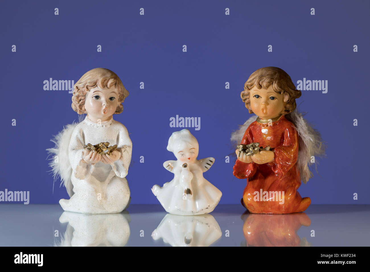 Closeup of three angels made of porcelain, blue background Stock Photo ...