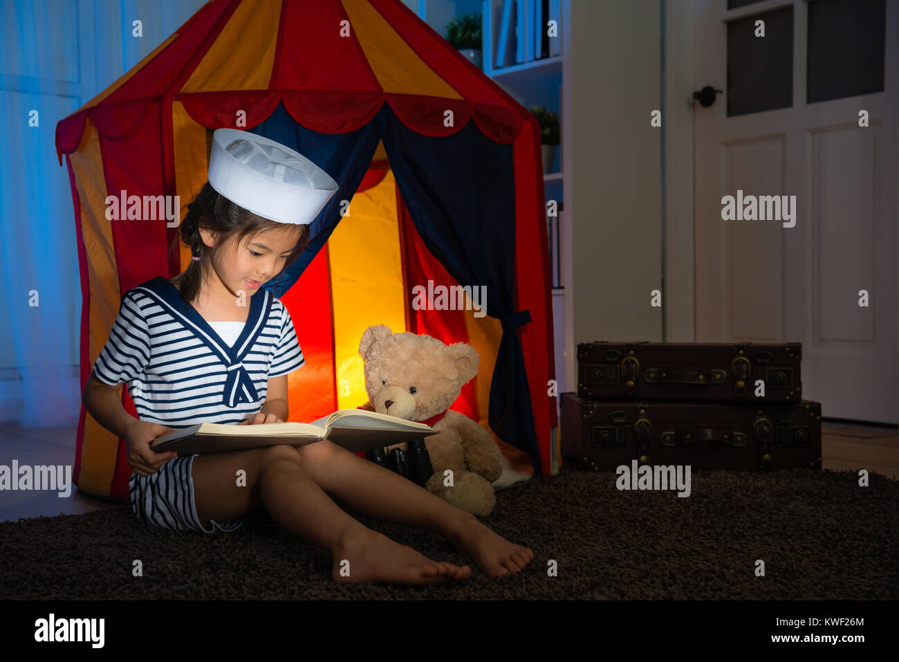 beautiful attractive little girl looking book talking with bear toy and ...