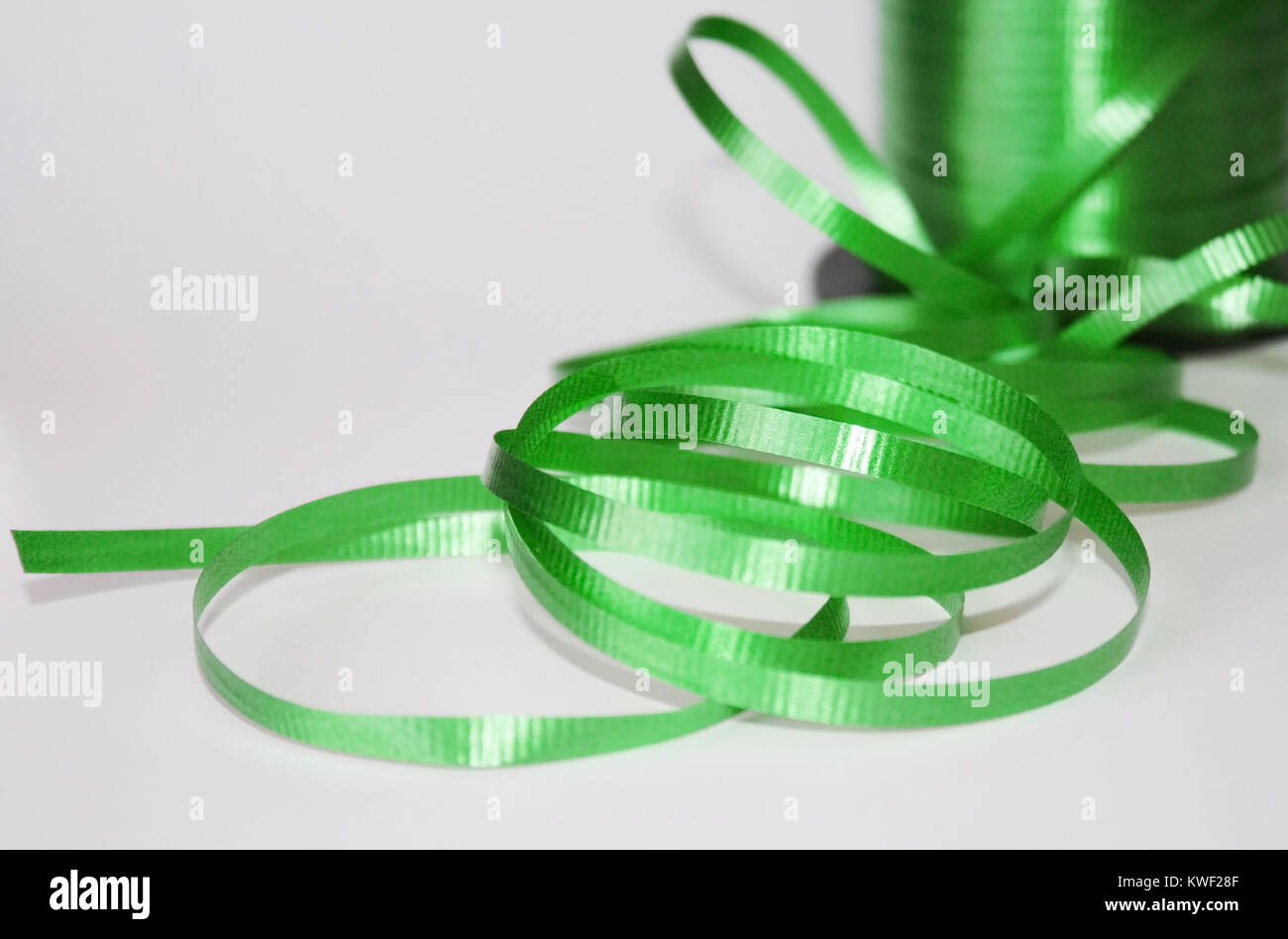 Spool of green curling ribbon on a white background Stock Photo - Alamy