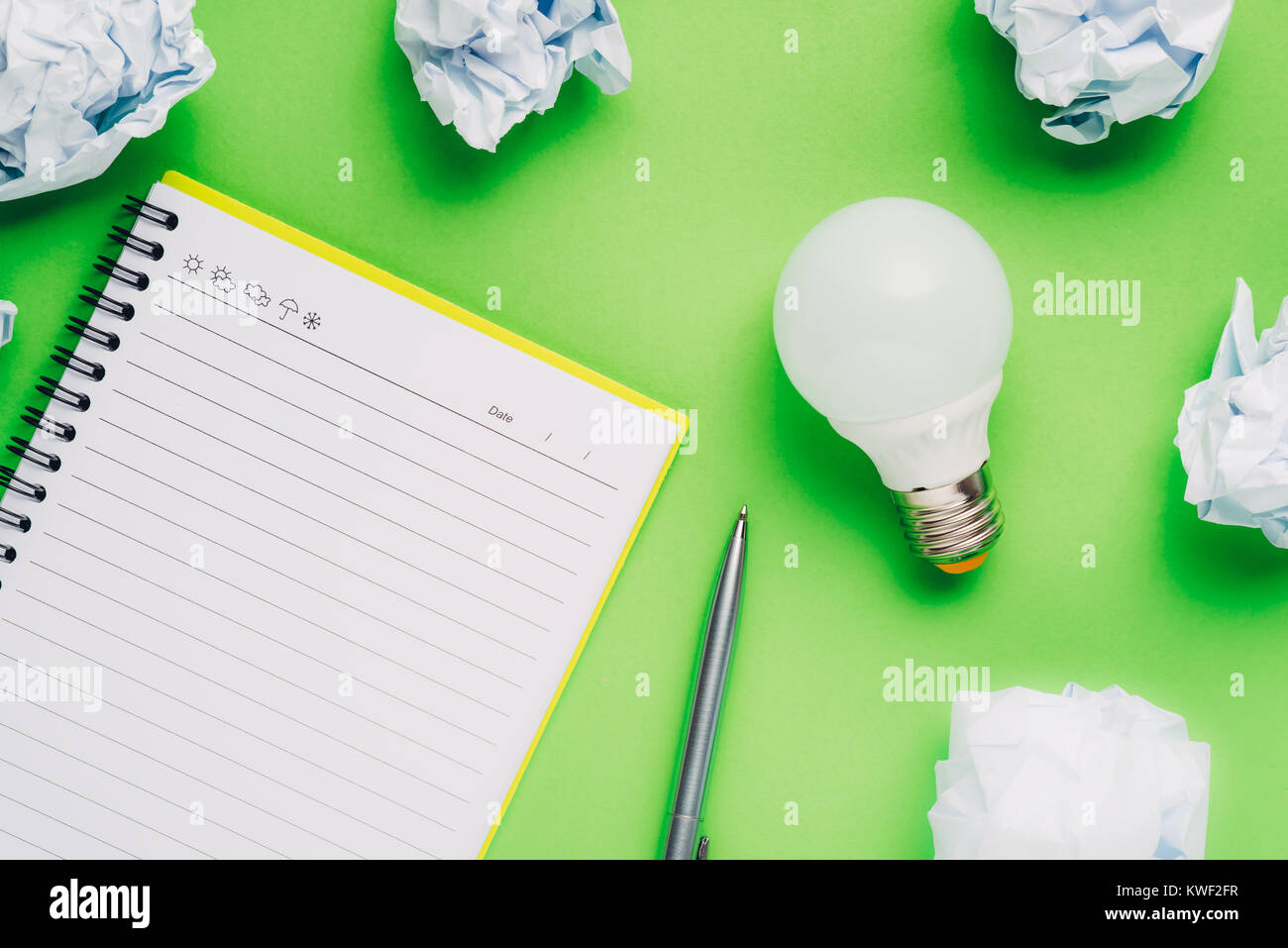 Note book and light bulb on green background Stock Photo - Alamy