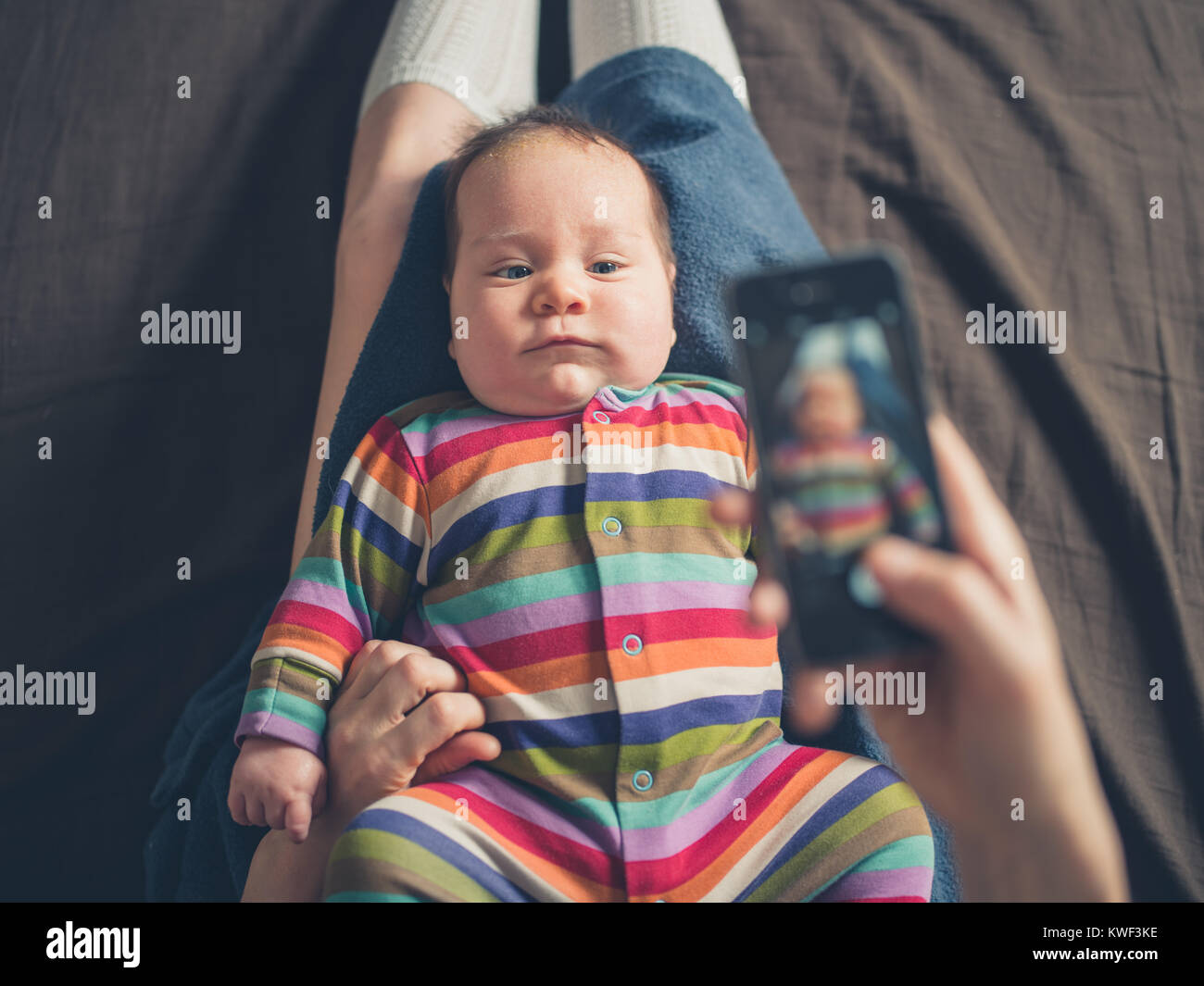 A mother is using her smartphone to take a photo of her baby Stock ...