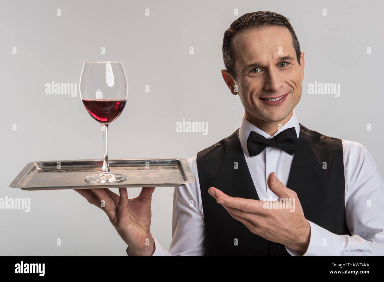 Your order. Jolly glad male waiter pointing at salver while looking at ...