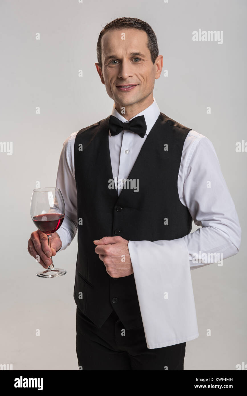 Excellent catering. Professional jolly male waiter standing on the grey ...