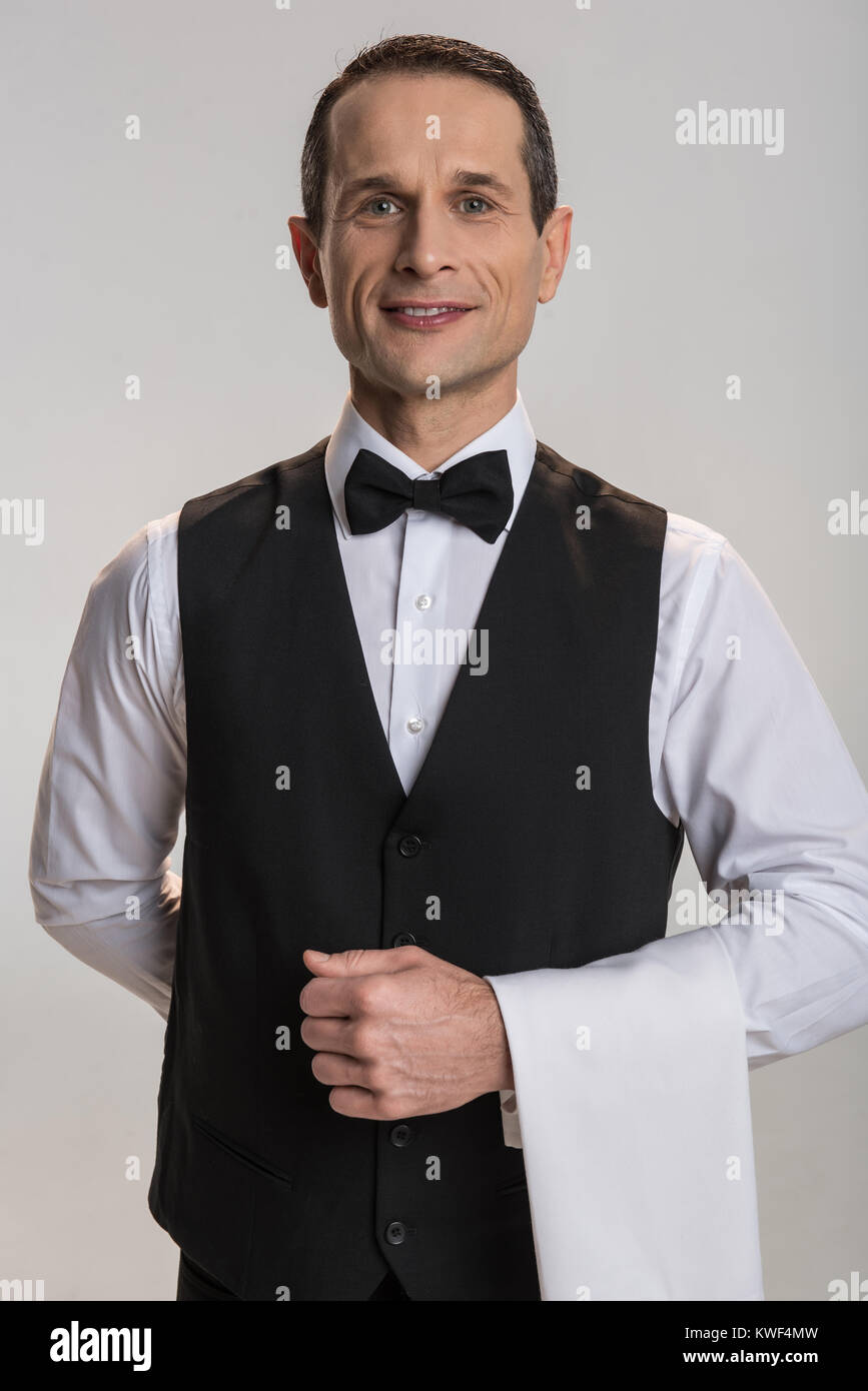 Perfect waiter. Merry attractive male waiter posing on the isolated ...