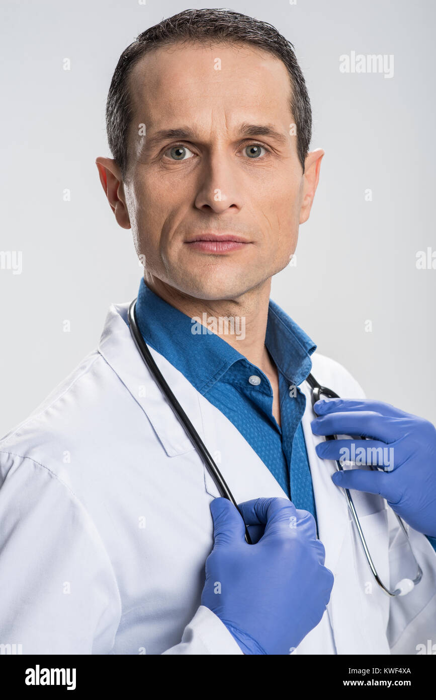 Working in process. Musing reflective male doctor touching stethoscope ...