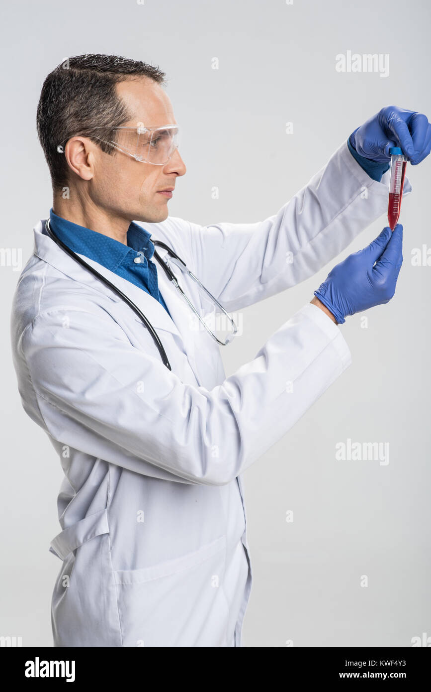 Blood sample. Serious attractive male laboritorian wearing lab coat ...