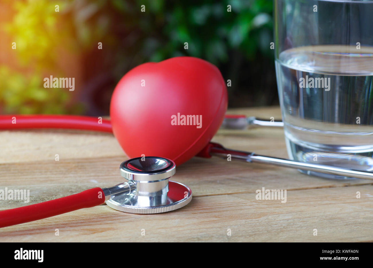 steth and red heart shape with glass of water on wood table, concept of ...