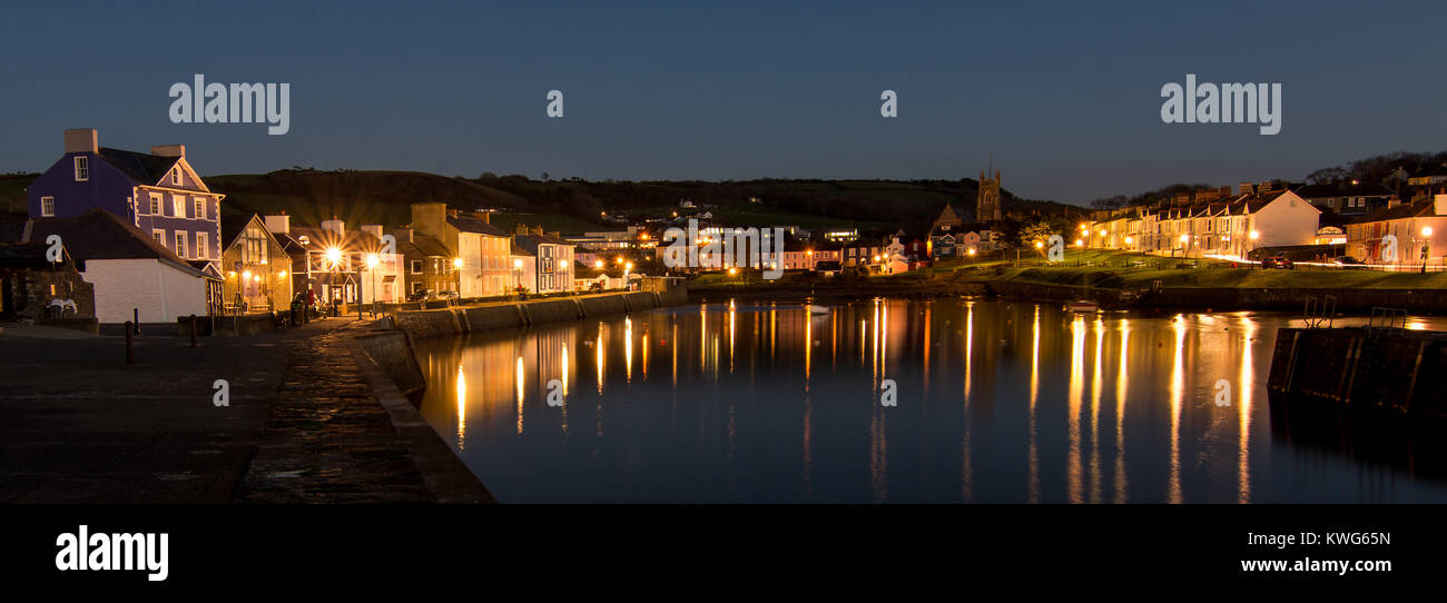 Quaint building overlooking a harbor at dusk, with lights reflecting on ...