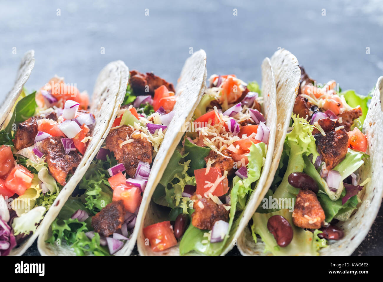 Four mexican tacos on a black background Stock Photo - Alamy