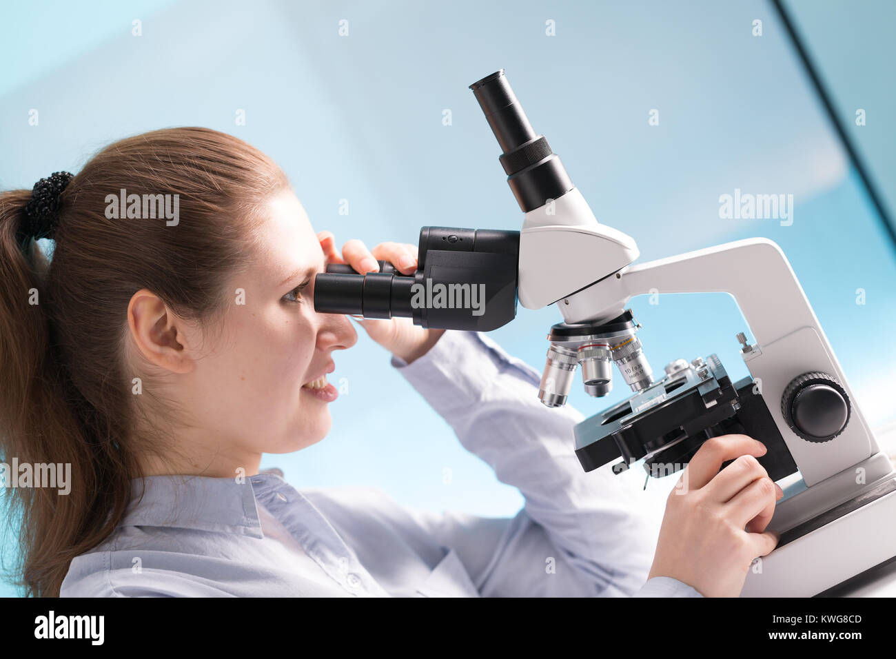 Doctor woman working a microscope. Female scientist looking through a ...