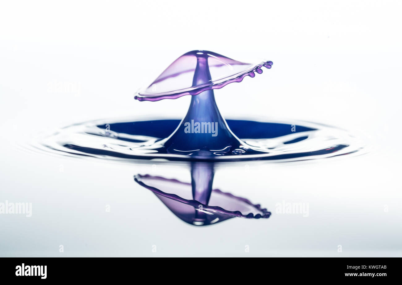 Splash and crown on rippled blue liquid or water surface . Water splash ...