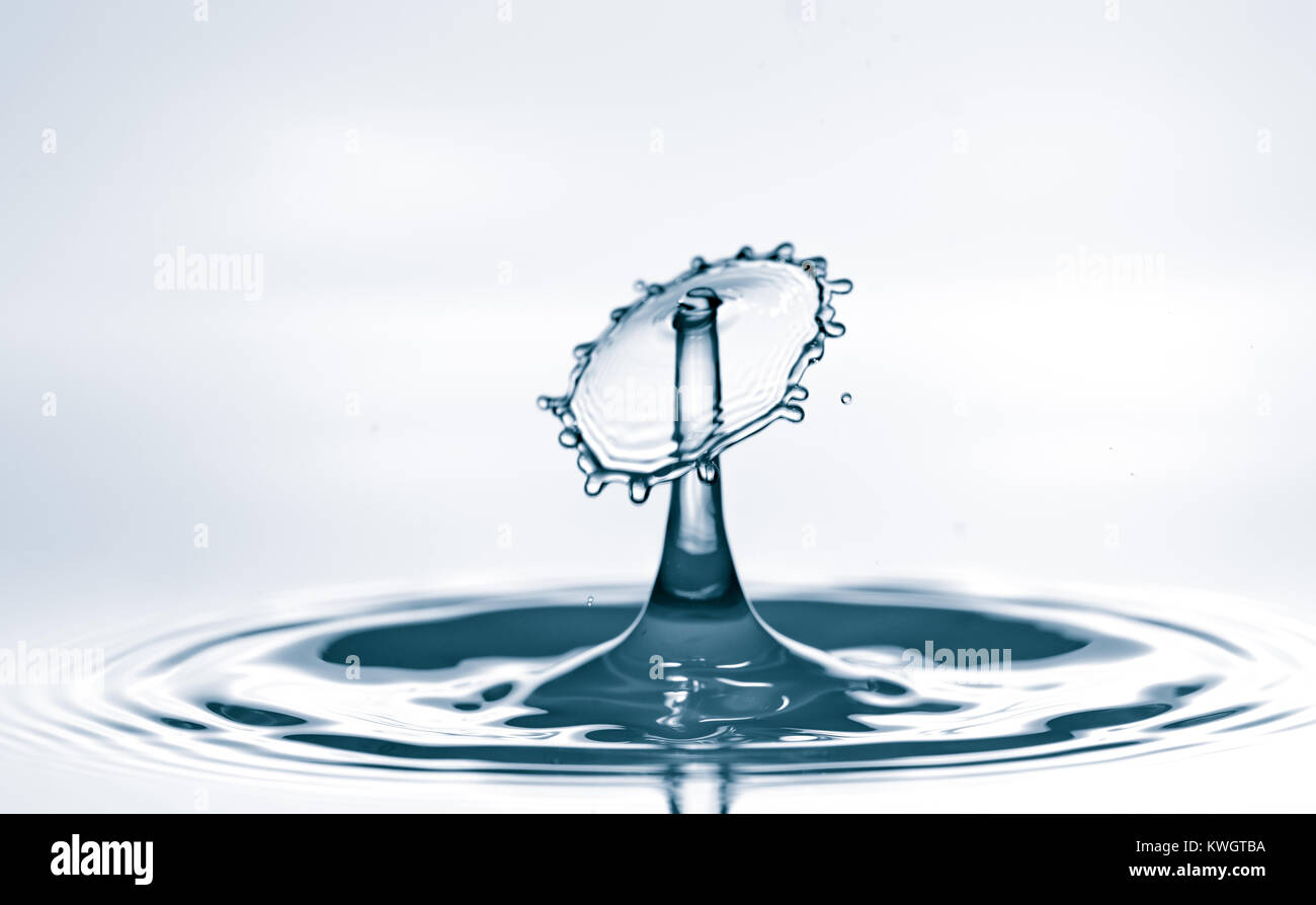 Splash and crown on rippled blue liquid or water surface . Water splash ...