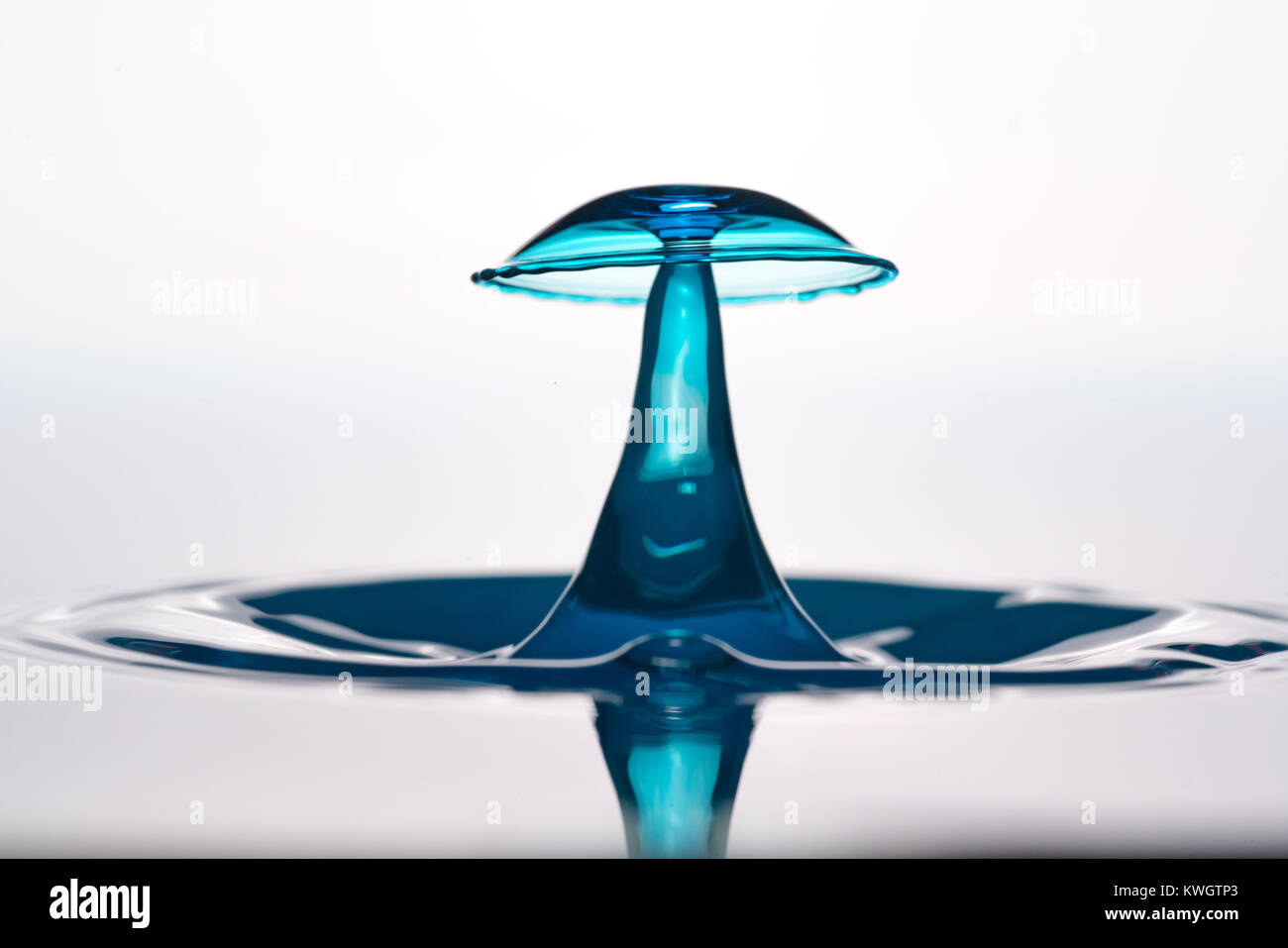 Splash and crown on rippled blue liquid or water surface . Water splash ...