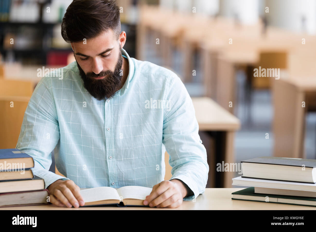 Serious male student reading book in the college library Stock Photo ...