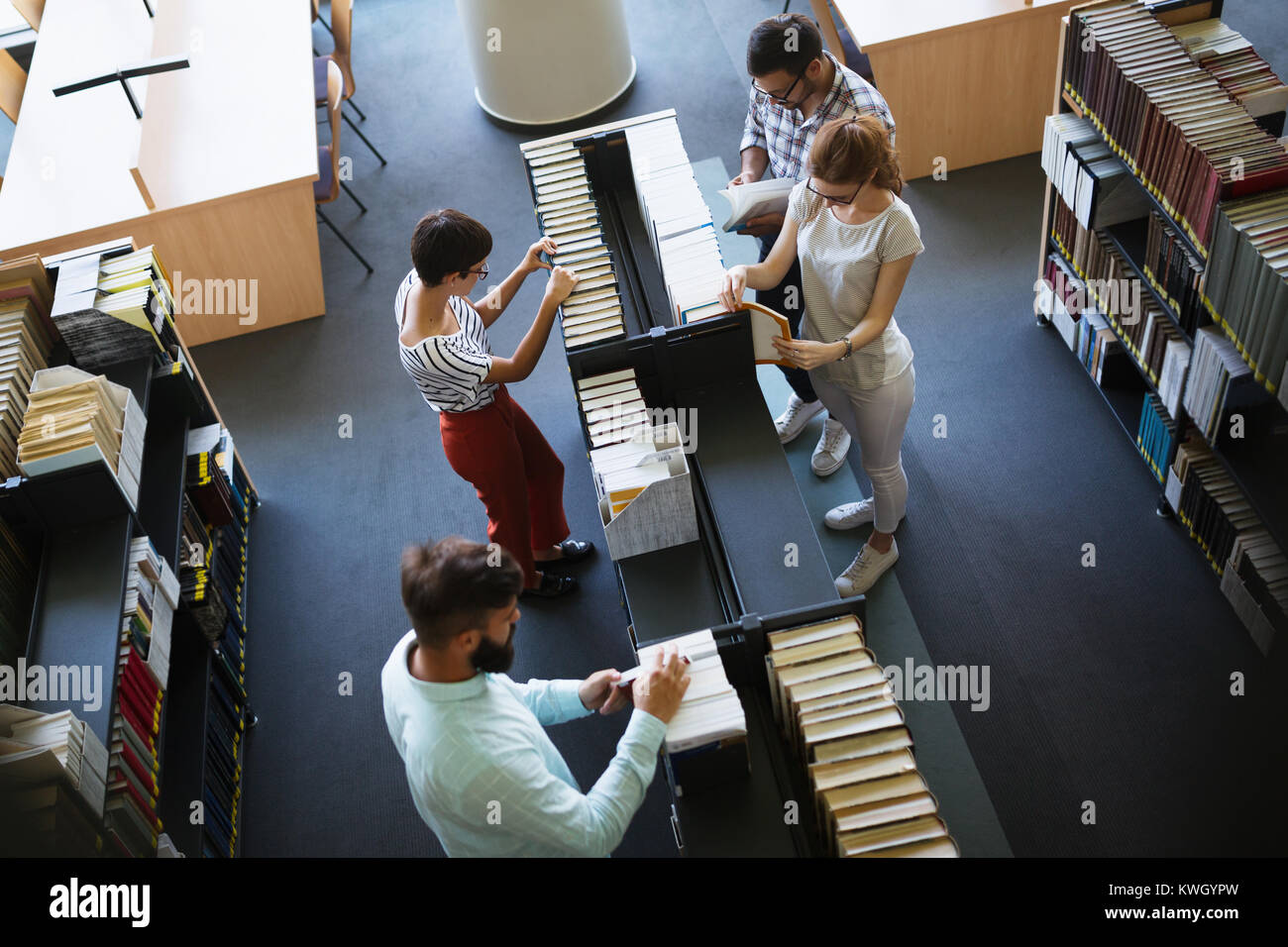 Happy young university students studying with books in library Stock ...