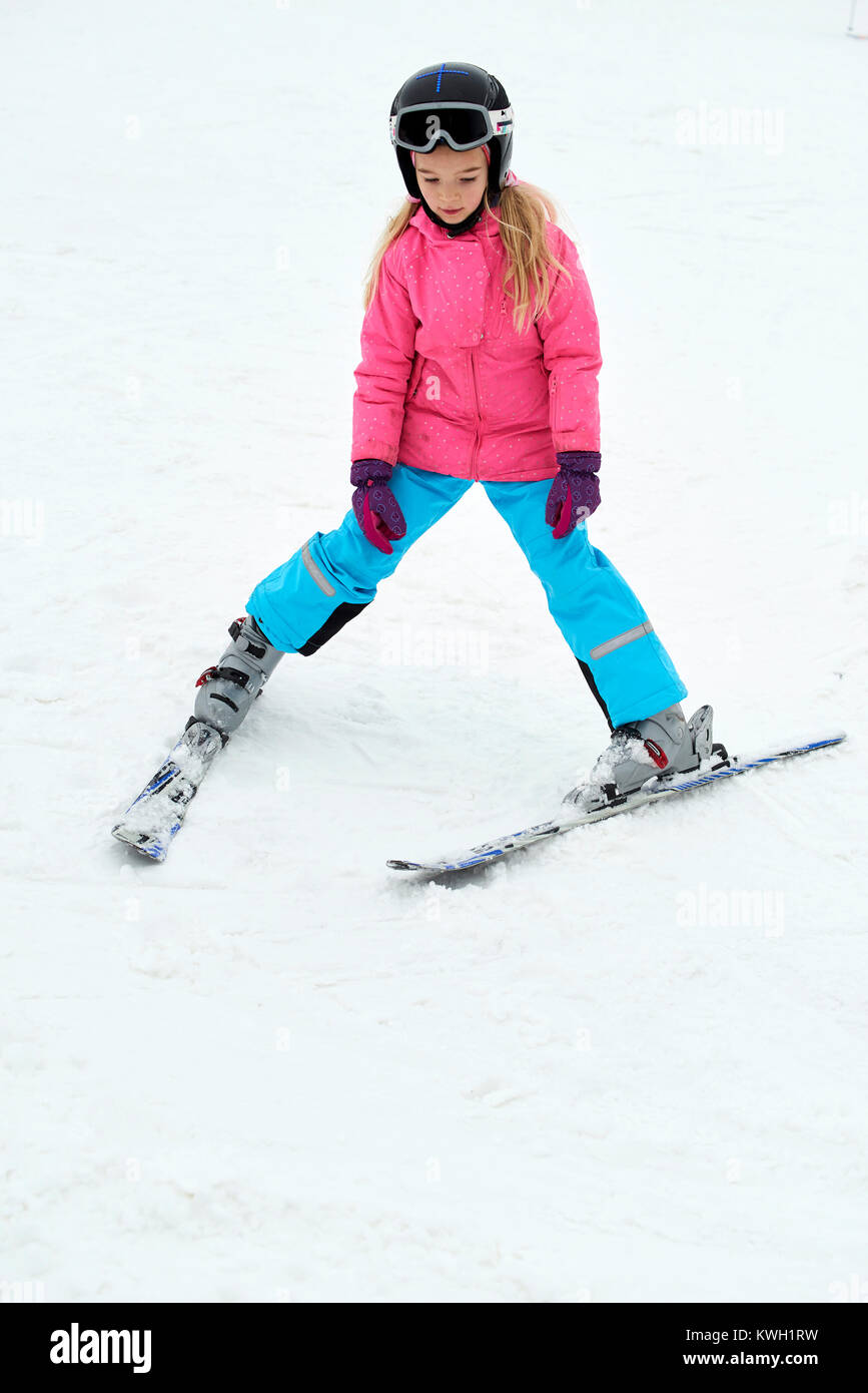 Child skiing in the mountains. Girl in colorful suit and safety helmet learning to ski. Winter ...