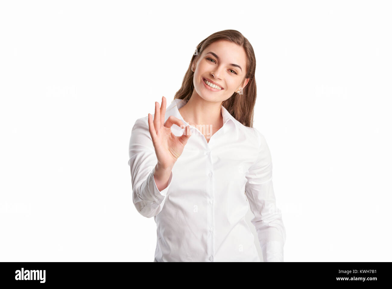 Beautiful young woman gesturing okay sign while standing at isolated ...
