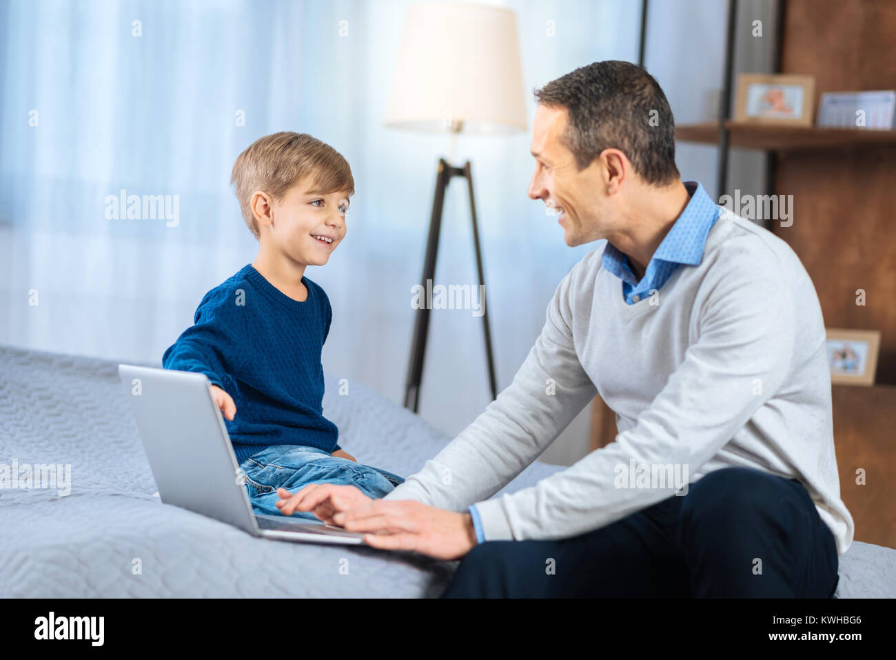Cheerful boy talking with his father on bed Stock Photo - Alamy