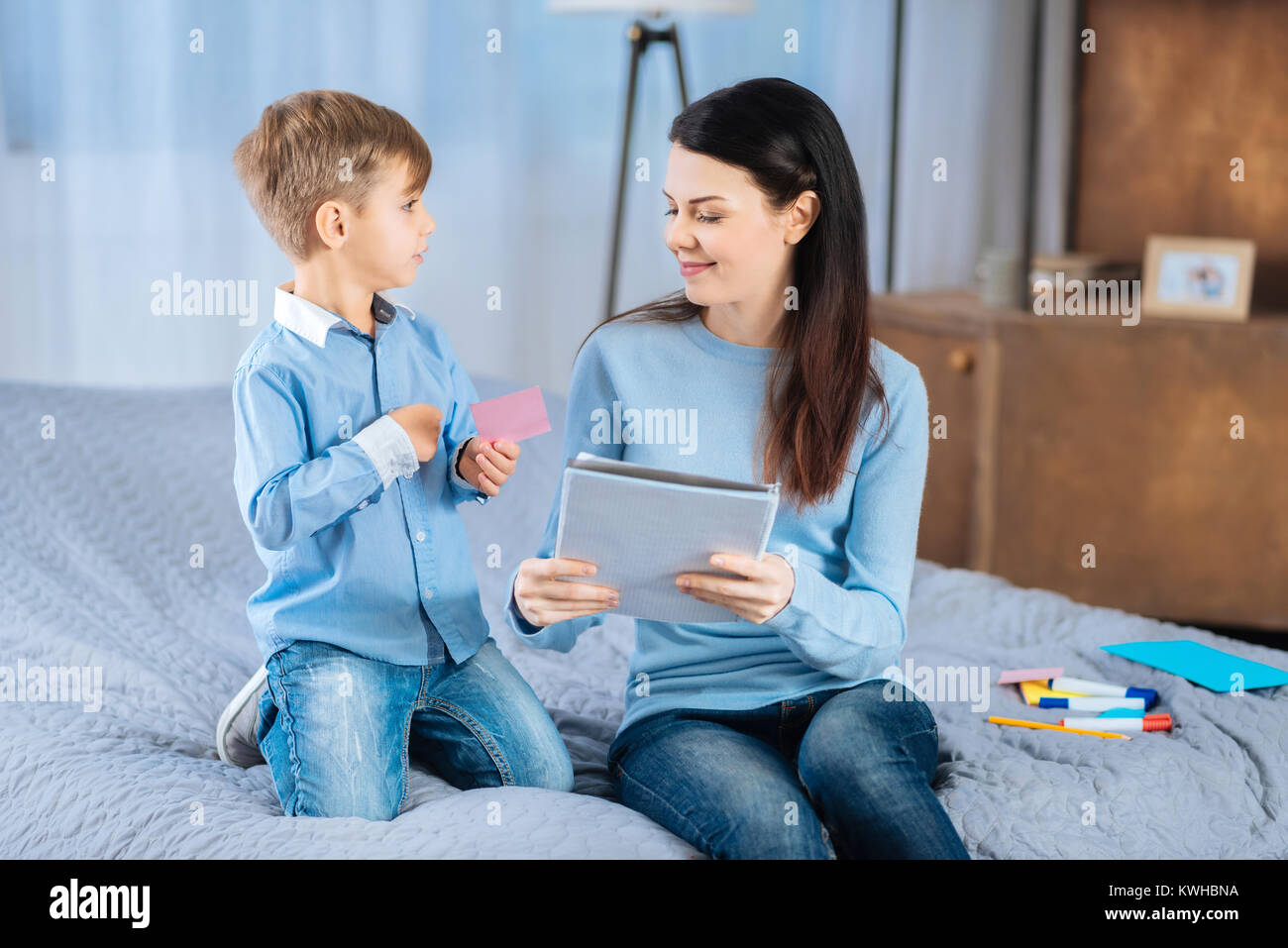 Little boy giving memo sticker to his mom holding notebook Stock Photo ...