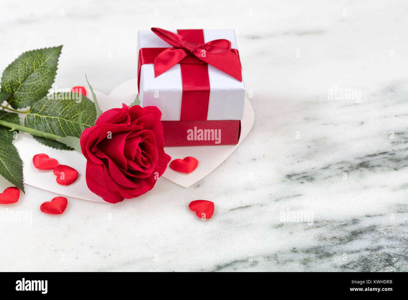 Single red rose with gift box and card on marble stone background in ...