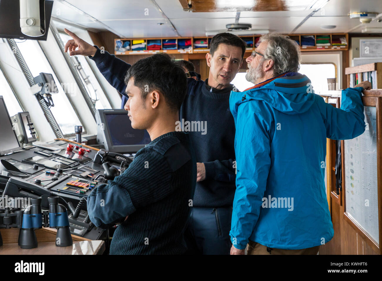 Tourist & ship's crew on bridge sailing passenger ship Ocean Adventurer ...