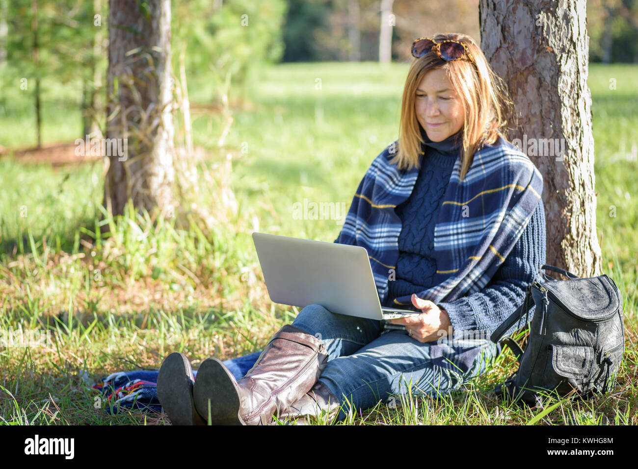 Woman on laptop under tree hi-res stock photography and images - Alamy