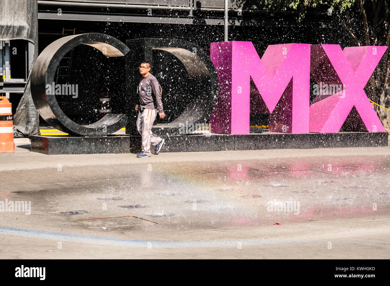 Commuters walking between a big CDMX sign and street fountain near a ...