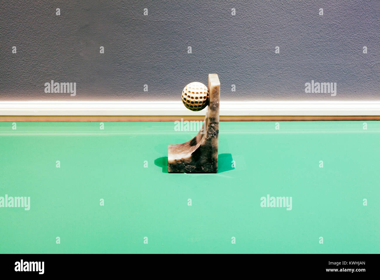 A golf ball with a marble base on top of a green glass table as an ...