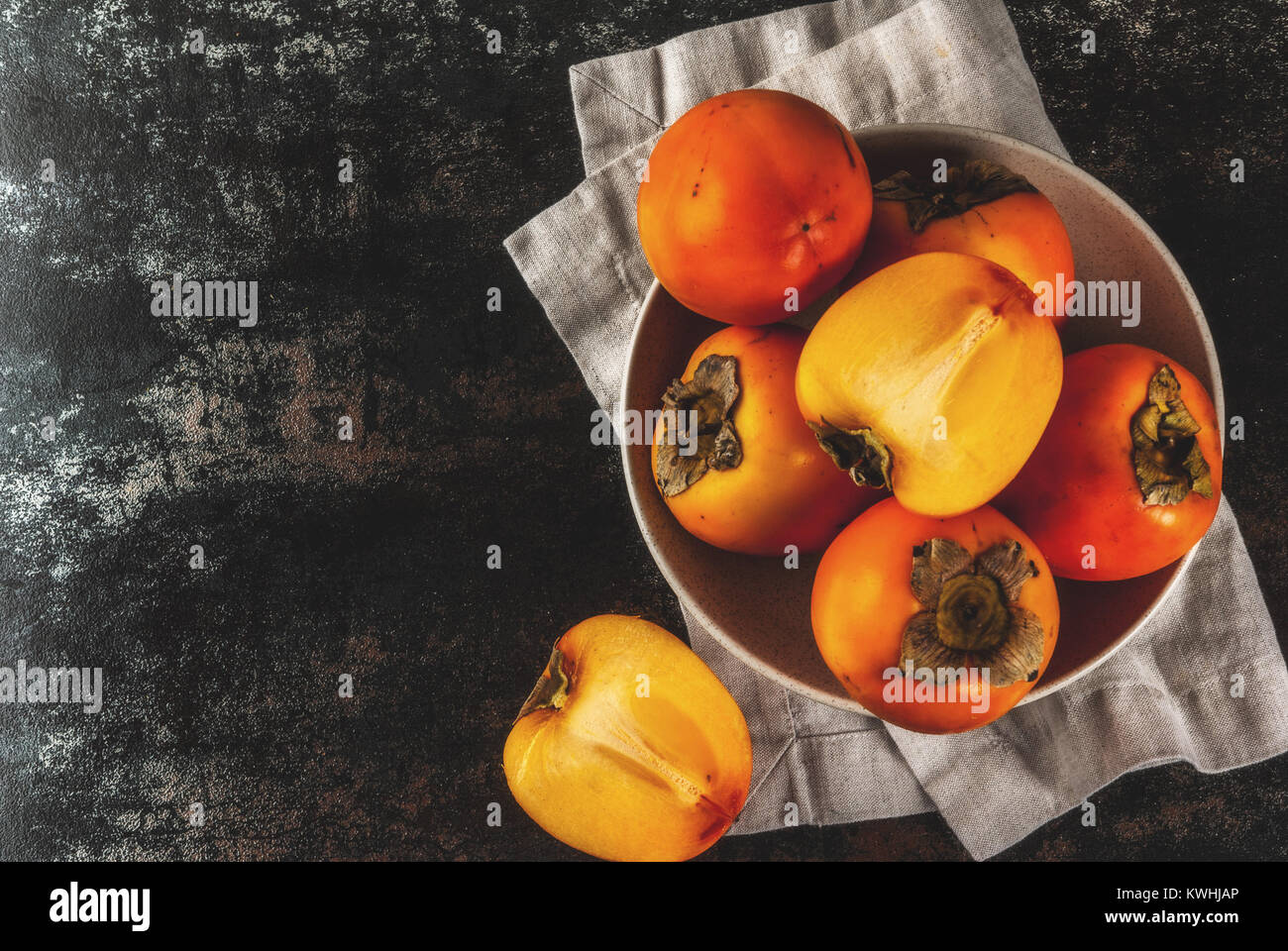 Delicious raw ripe persimmon fruit on dark rusty metal background copy ...