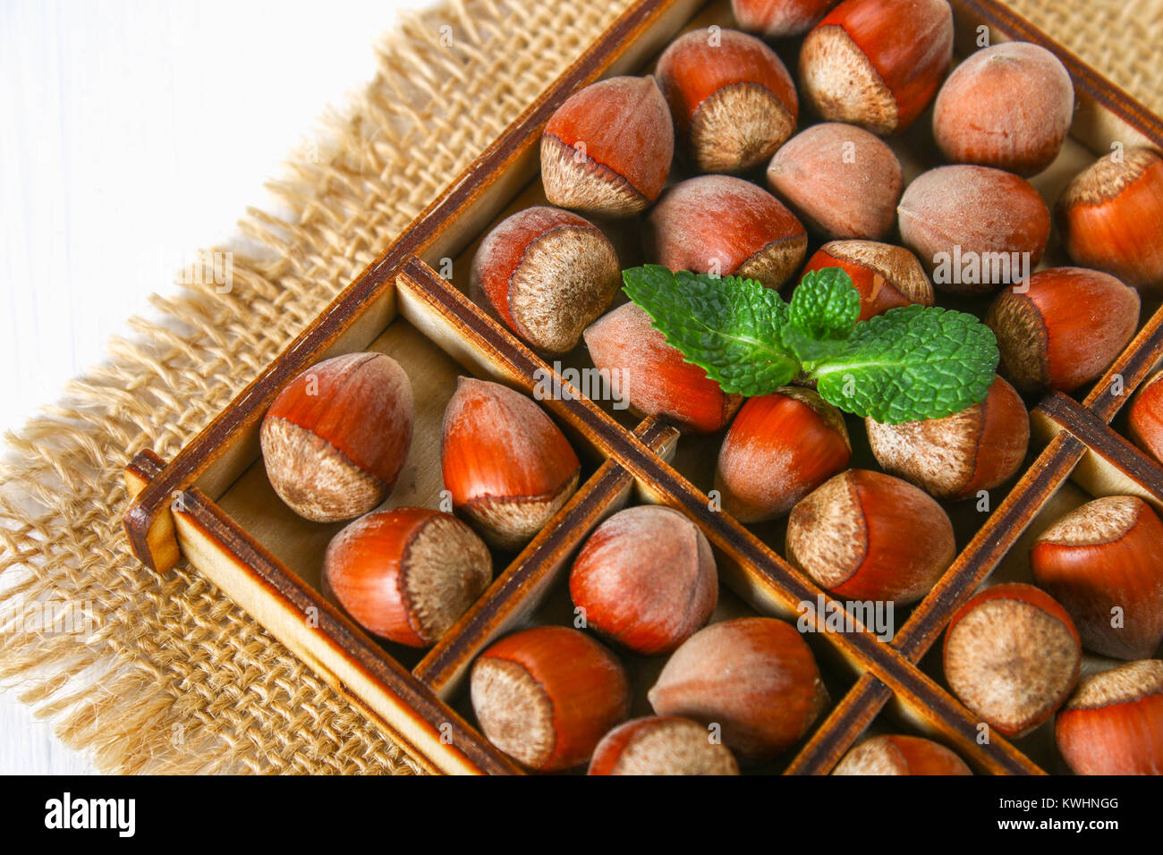 Walnut hazelnuts in a square wooden box with dividers on a white wooden ...