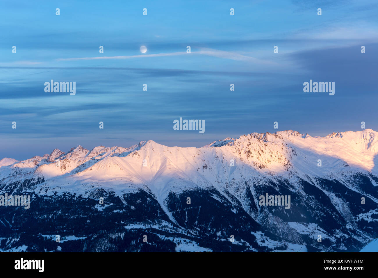 Glowing snowy mountains during sunset in the alps with the full moon ...