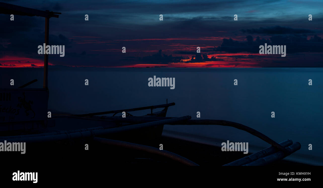Sunset over the pacific ocean with a traditional bamboo wooden vessel ...