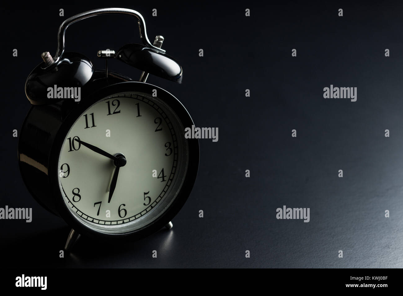 Black alarm clock on black background Stock Photo - Alamy