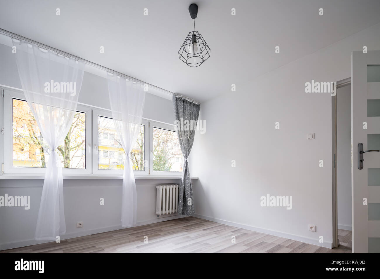 Bright, empty room with industrial wire lamp and window curtains Stock ...