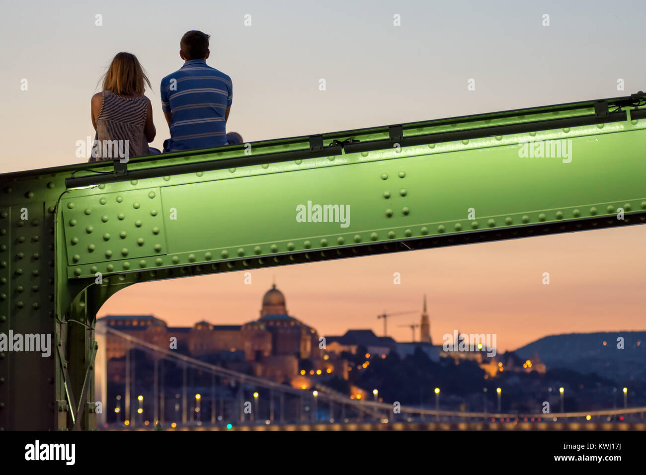 Young couple watching cityscape sitting on bridge beam Stock Photo - Alamy