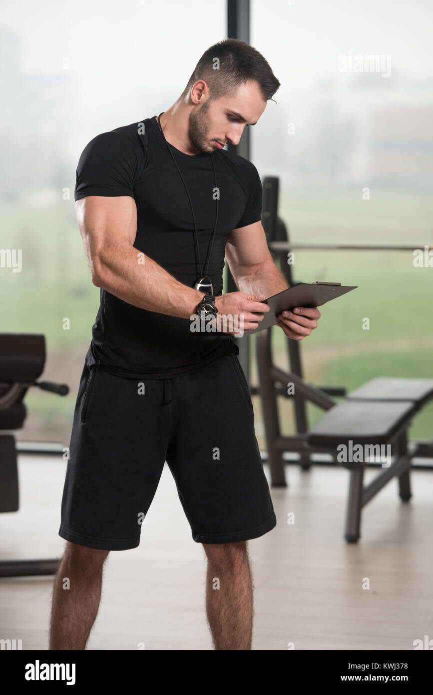 Personal Trainer Takes Notes On Clipboard In Fitness Center Gym Stock ...